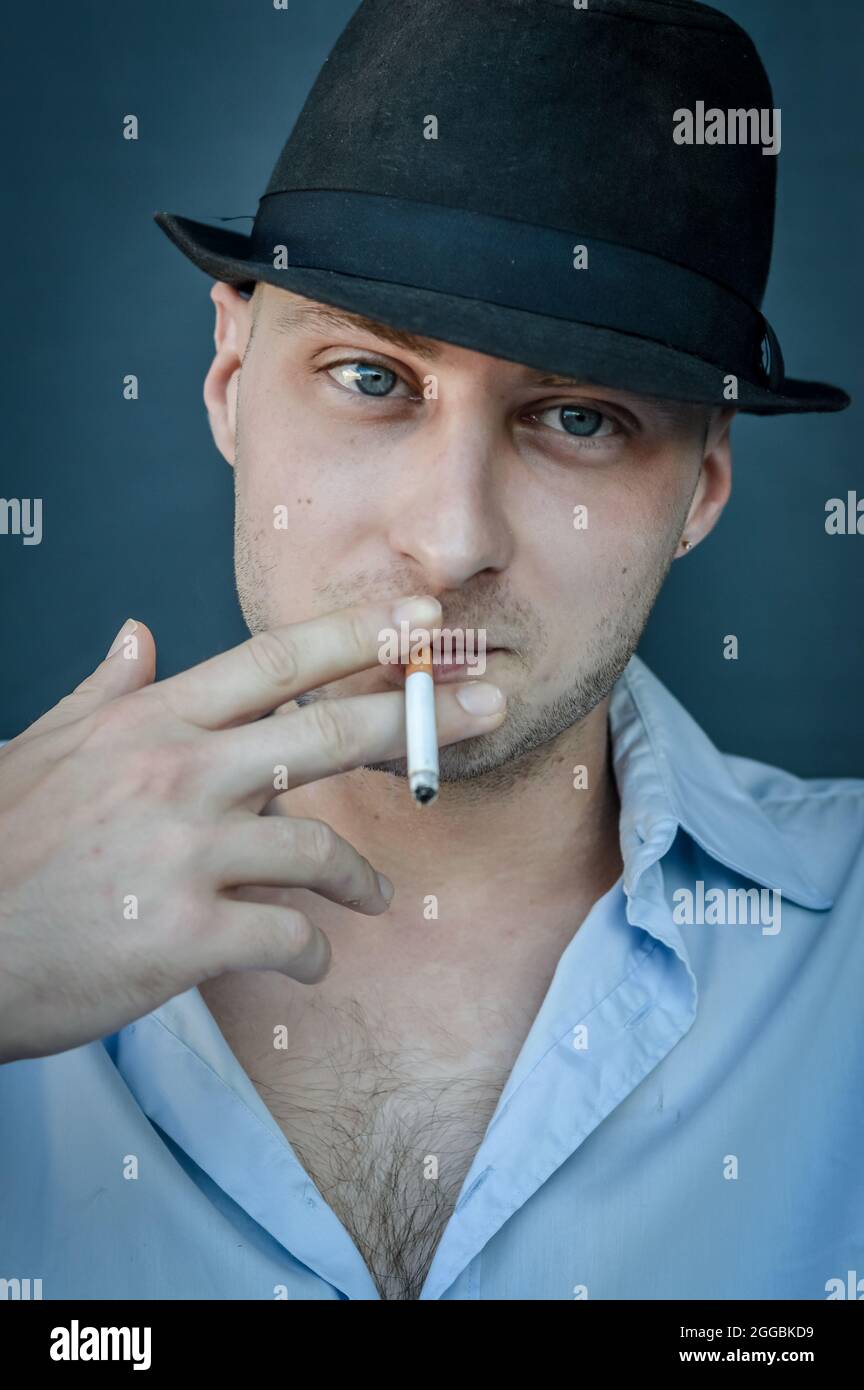 portrait of a young bald man smoking a cigarette while relaxing and ...