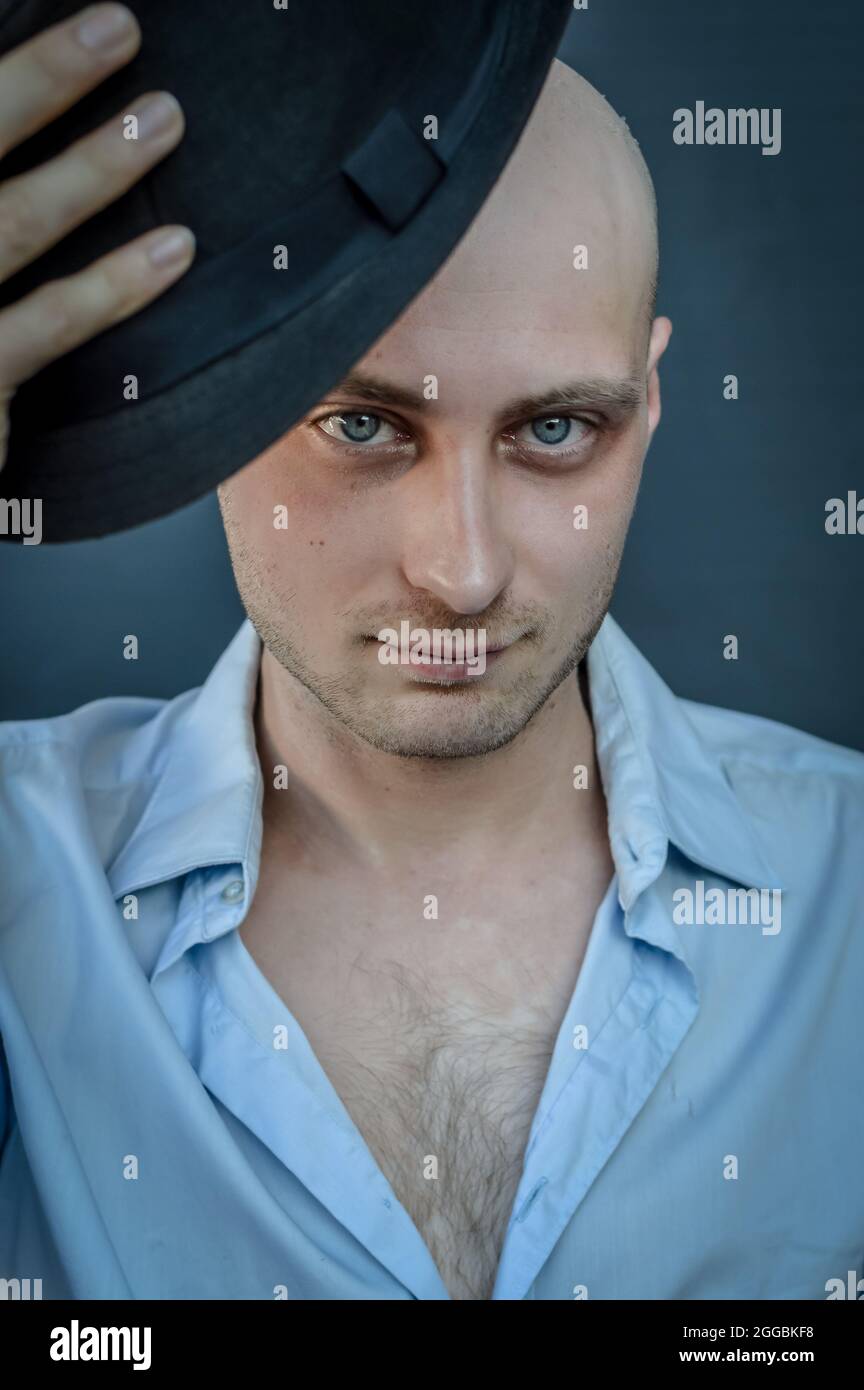 portrait of a young man holding his hat off his head with his hand ...