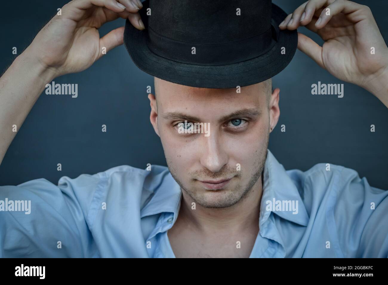 portrait of a young man holding his hat off his head with his hands ...