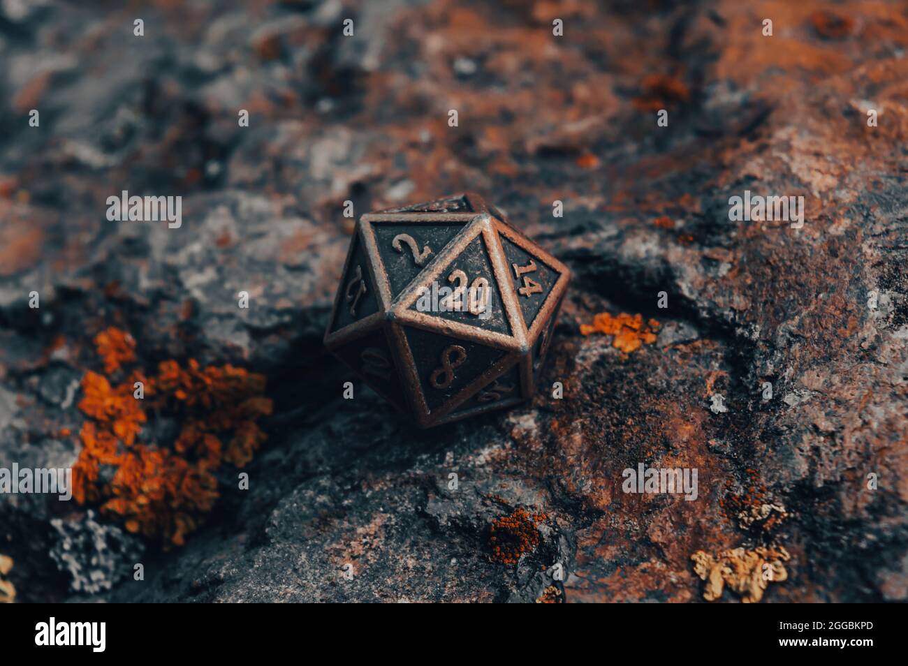 Close-up image of one 20-sided metallic role-playing die on rock ...