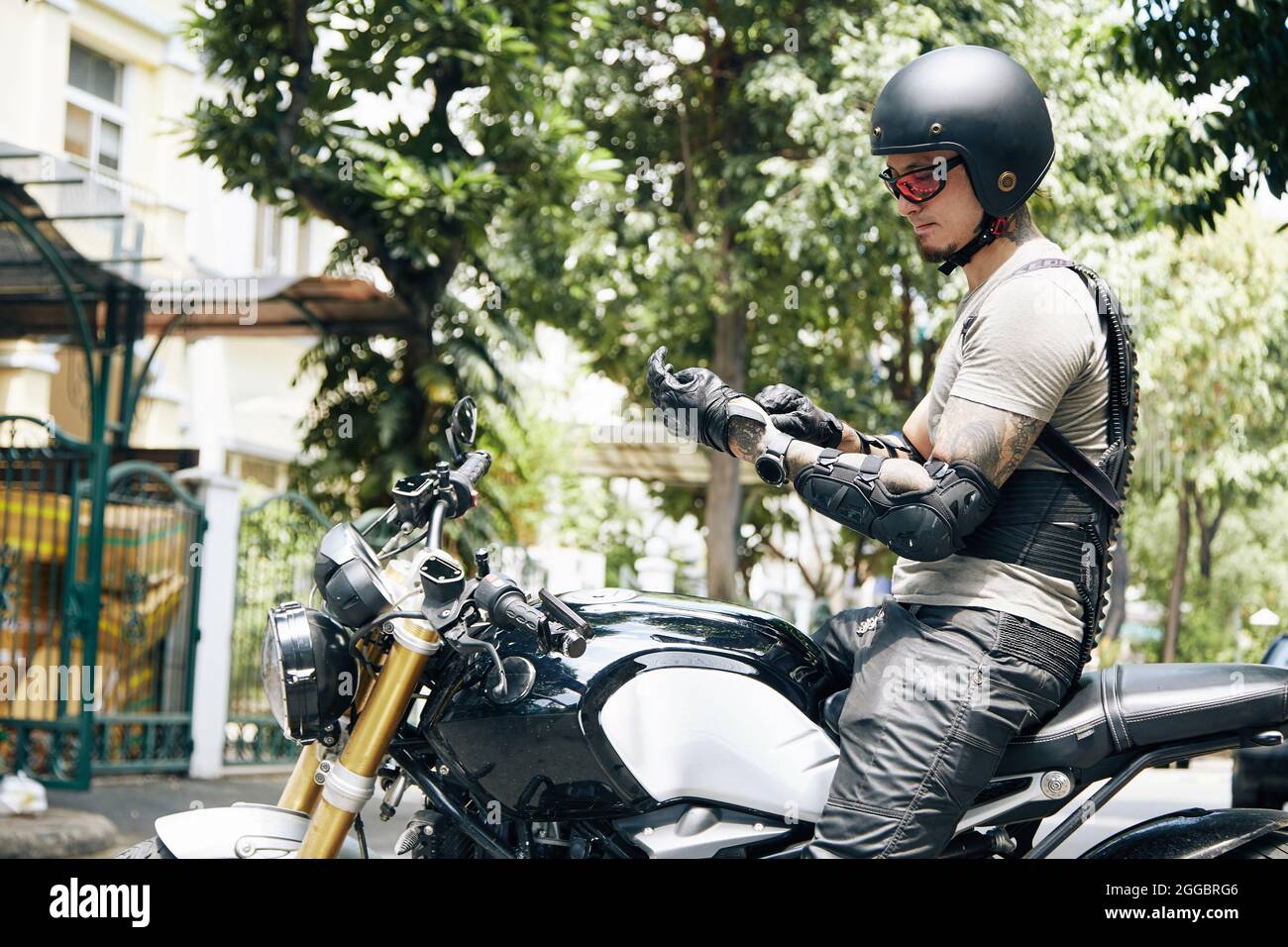 Handsome serious man sitting on motorcycle and putting on leather ...