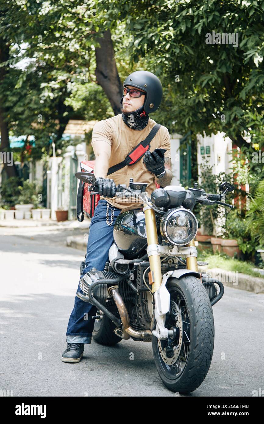Courier in protective helmet working as courier and delivering food to ...