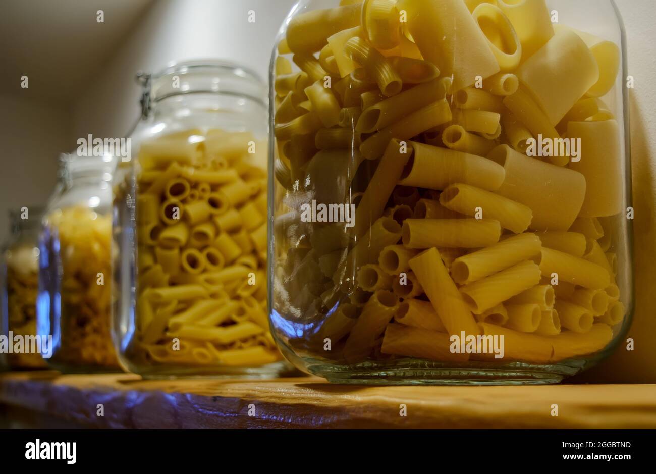Four glass jars standing on the shelf and filled with various types of ...