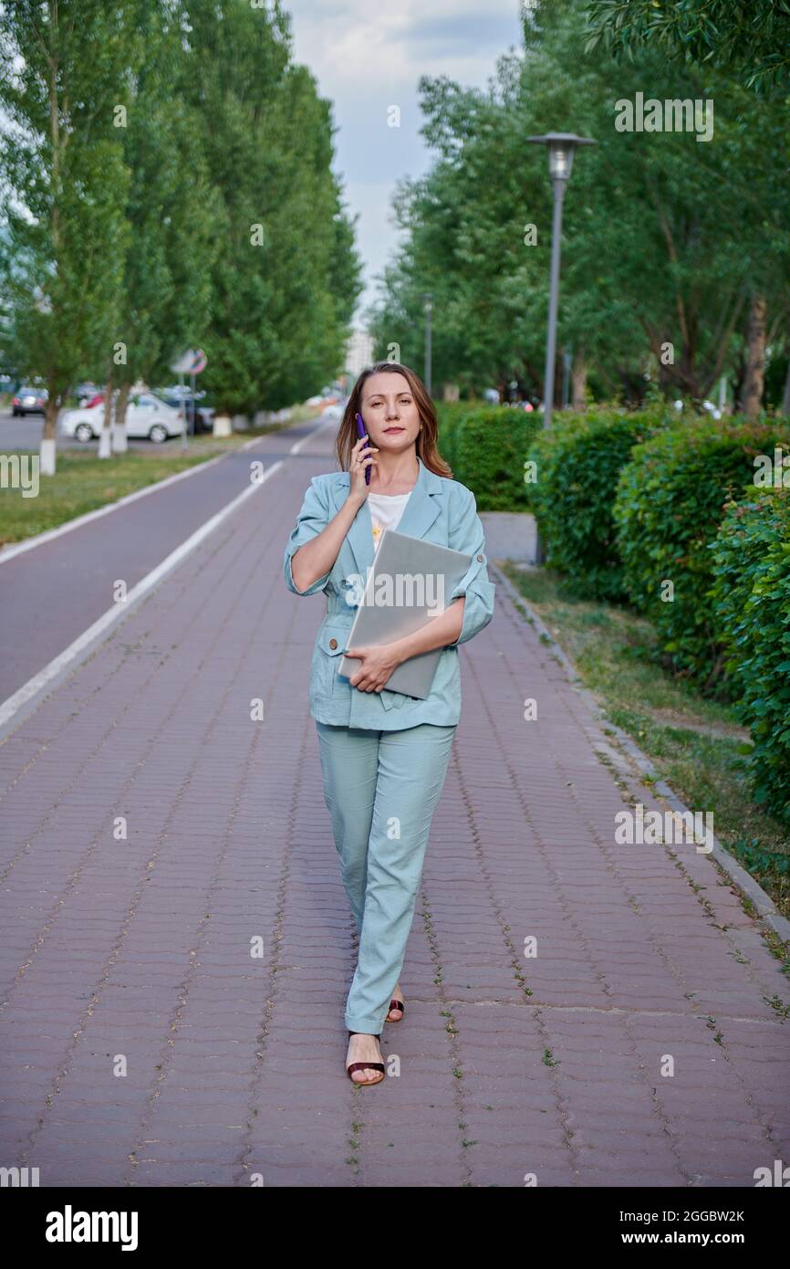 nimble business woman walking along the sidewalk with a laptop Stock ...