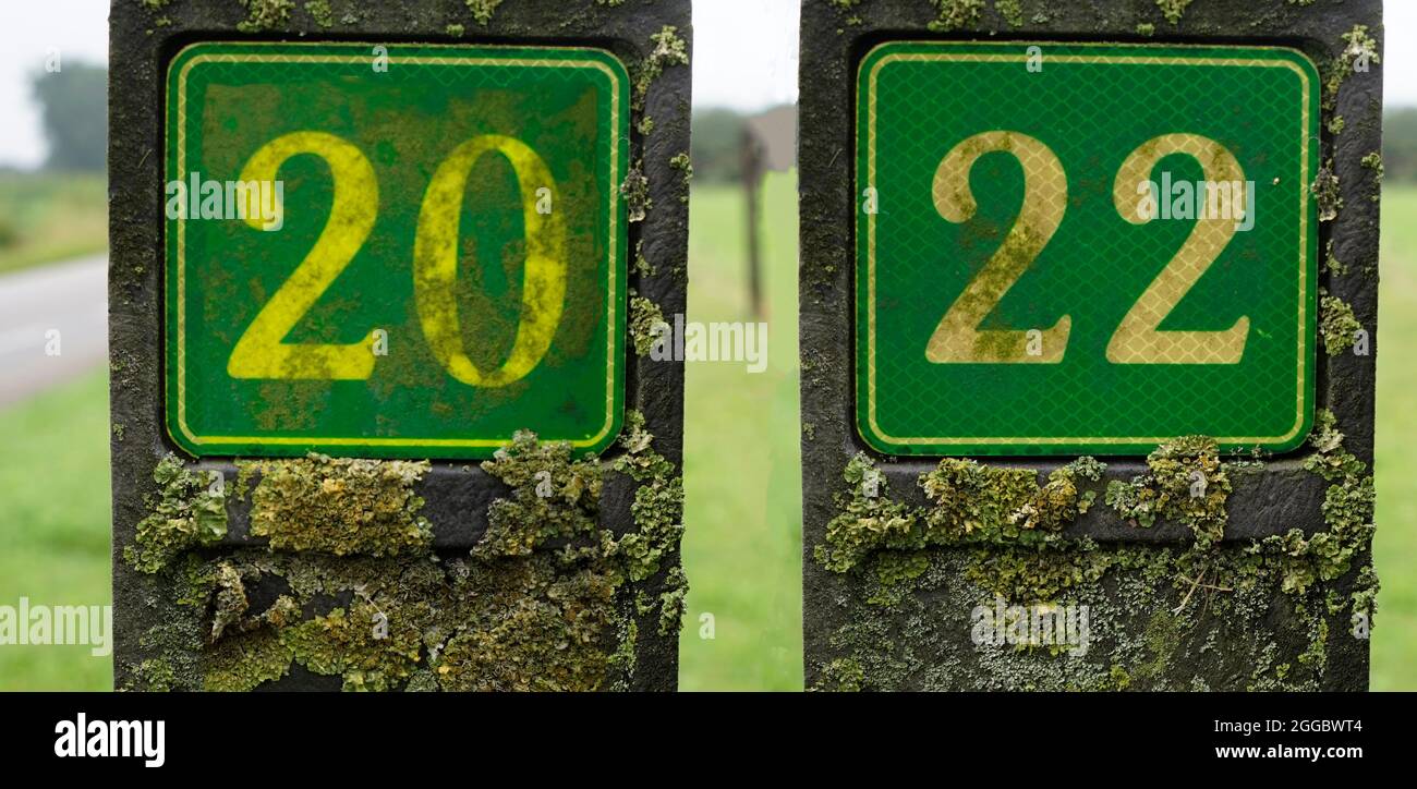 Two green number shields at the road. The concrete posts are covered ...