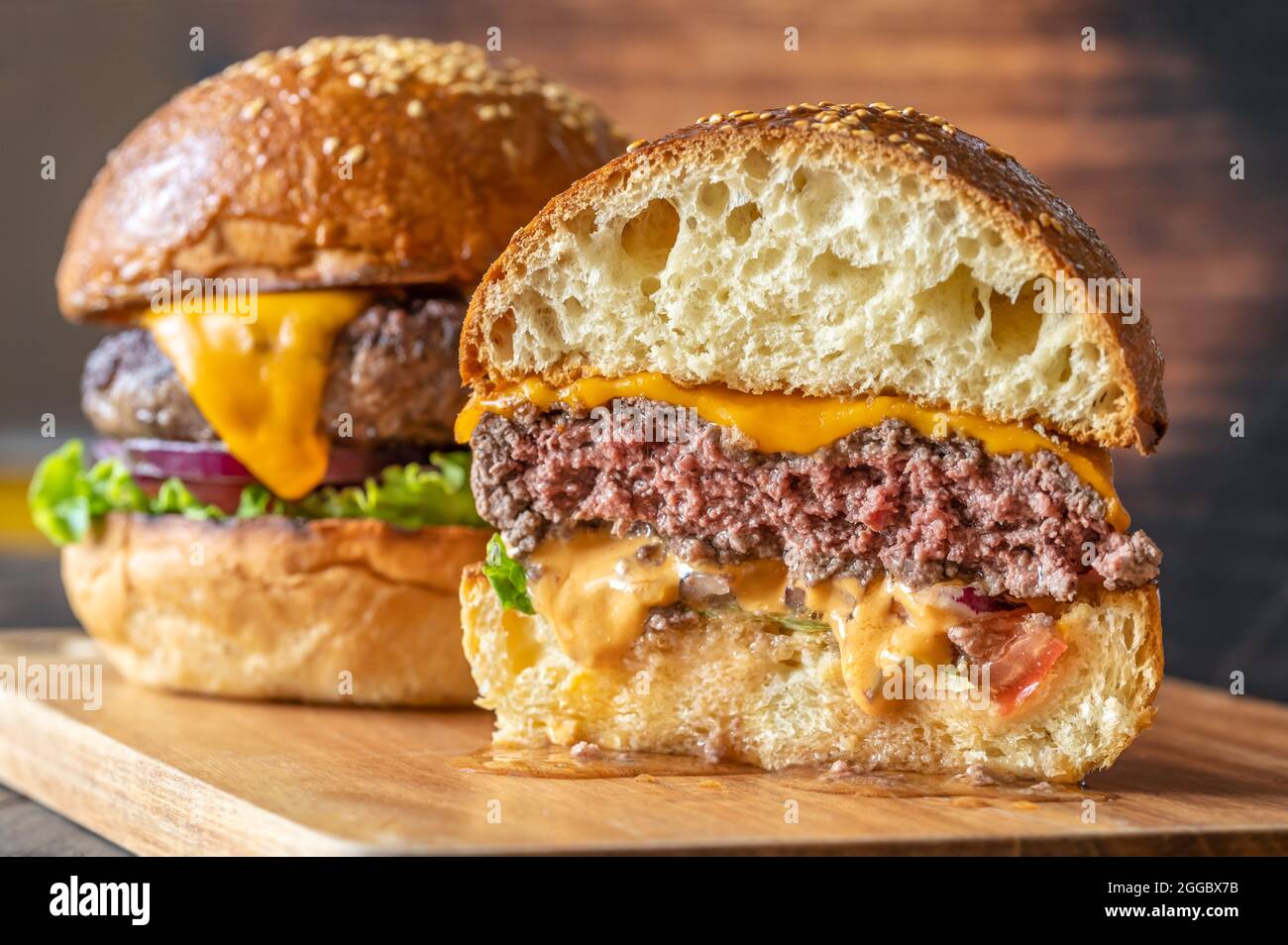 Two burgers on the wooden board close up Stock Photo - Alamy
