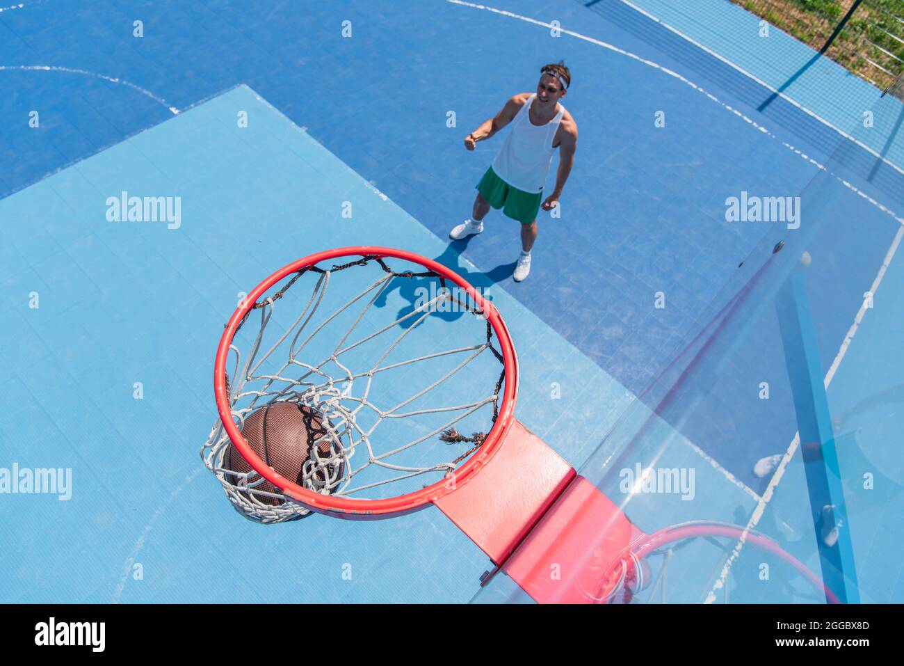 Top view of basketball ball in hoop near blurred sportsman on ...