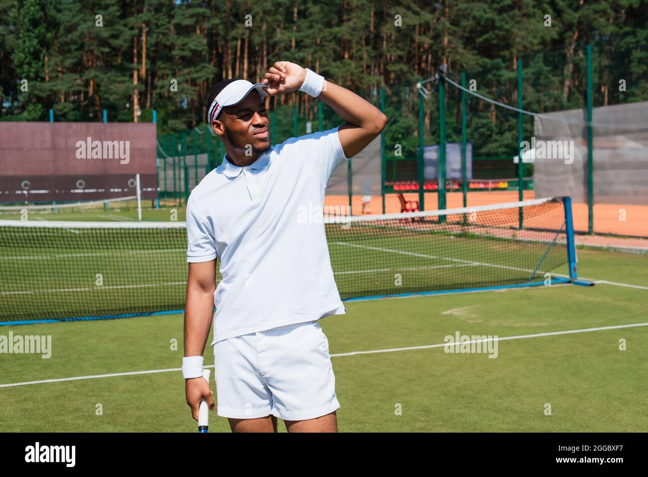 African american tennis player holding racket and looking away on court ...