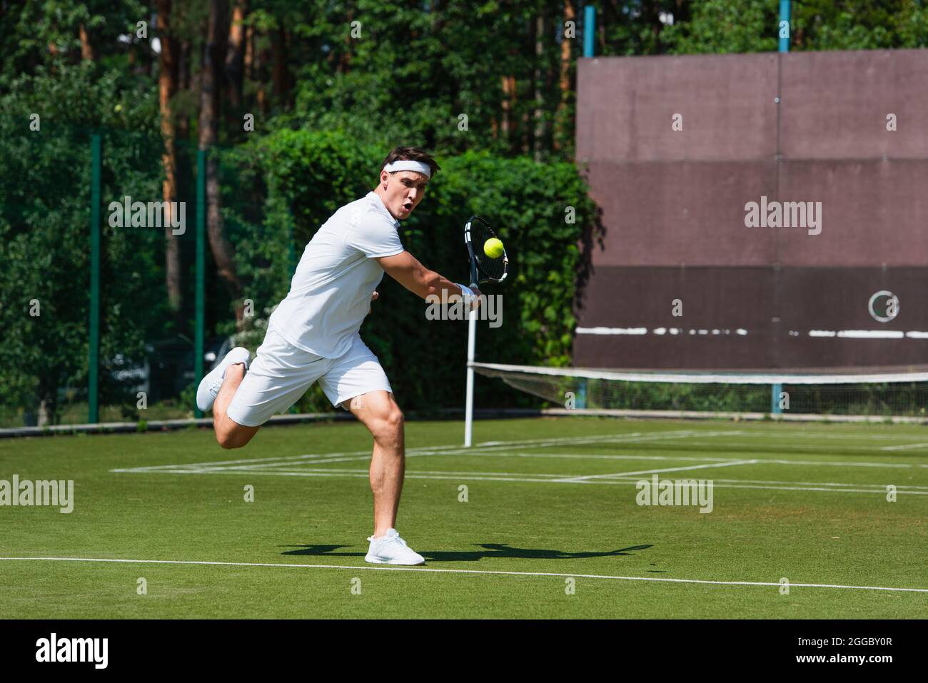 Young sportsman running while playing tennis on court Stock Photo - Alamy