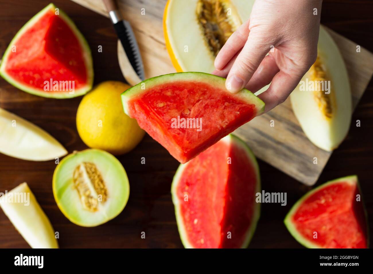 Hand holding slice of watermelon; variety of melons Stock Photo - Alamy