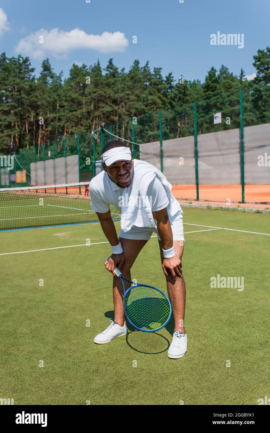 Tired african american sportsman holding tennis racket on court Stock ...