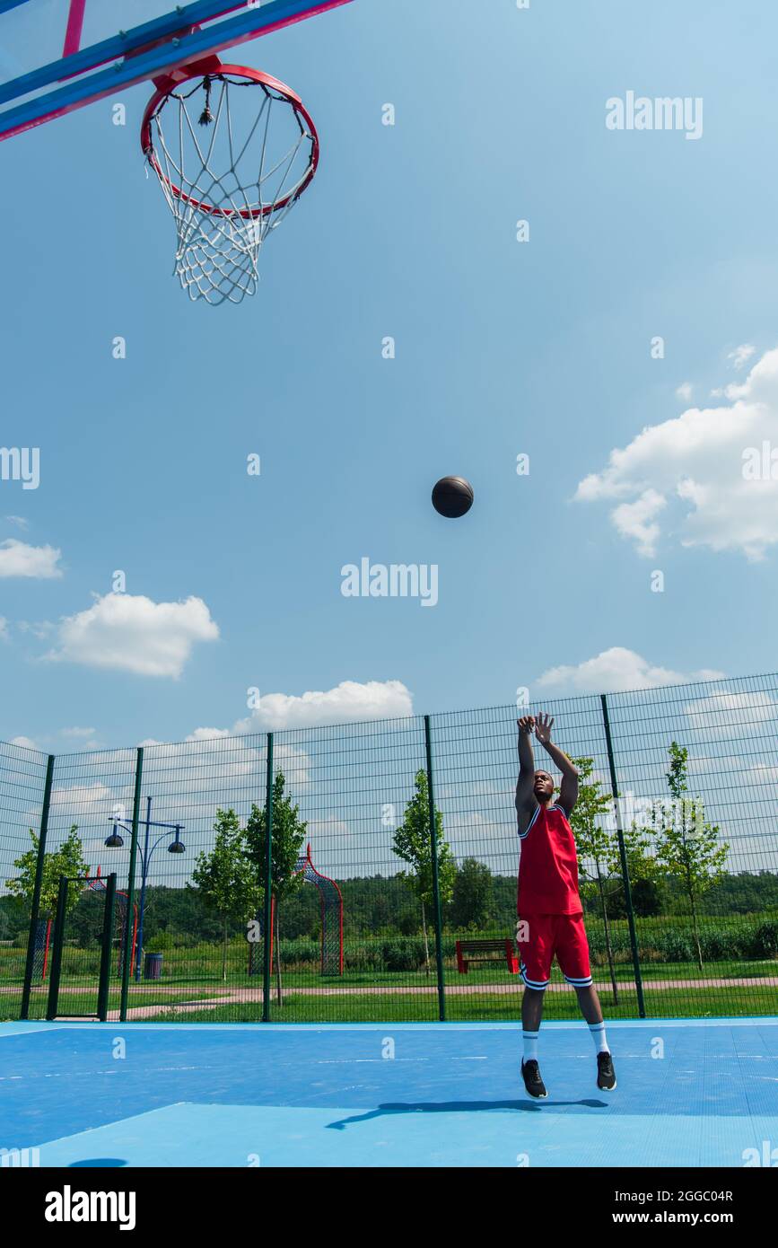 African american player throwing basketball ball in hoop on playground ...