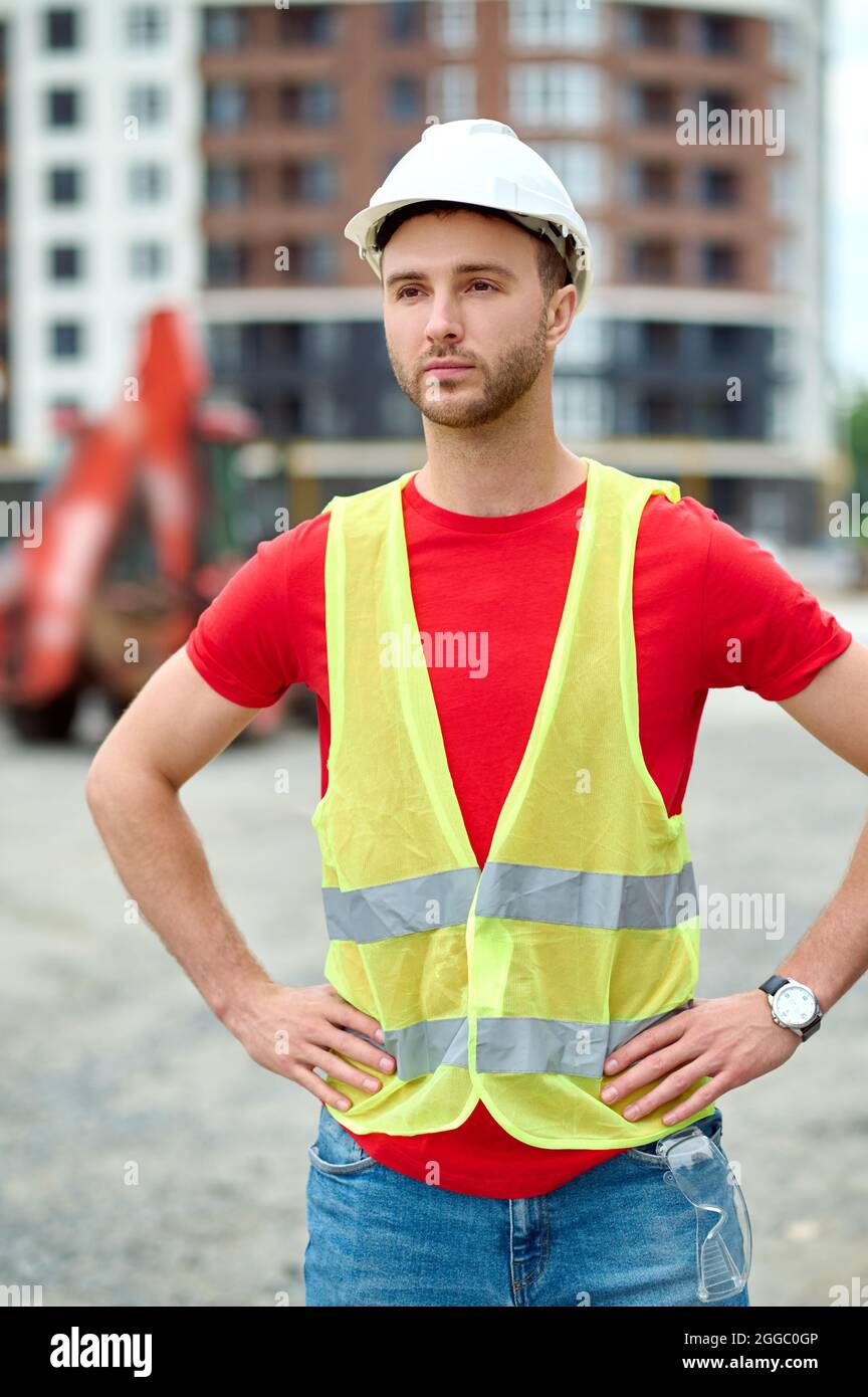 Worker in a safety vest and a helmet standing outdoors Stock Photo - Alamy