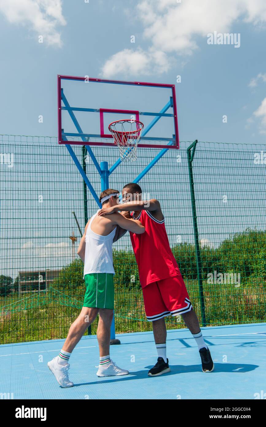 Multiethnic sportsmen hugging on streetball playground Stock Photo - Alamy
