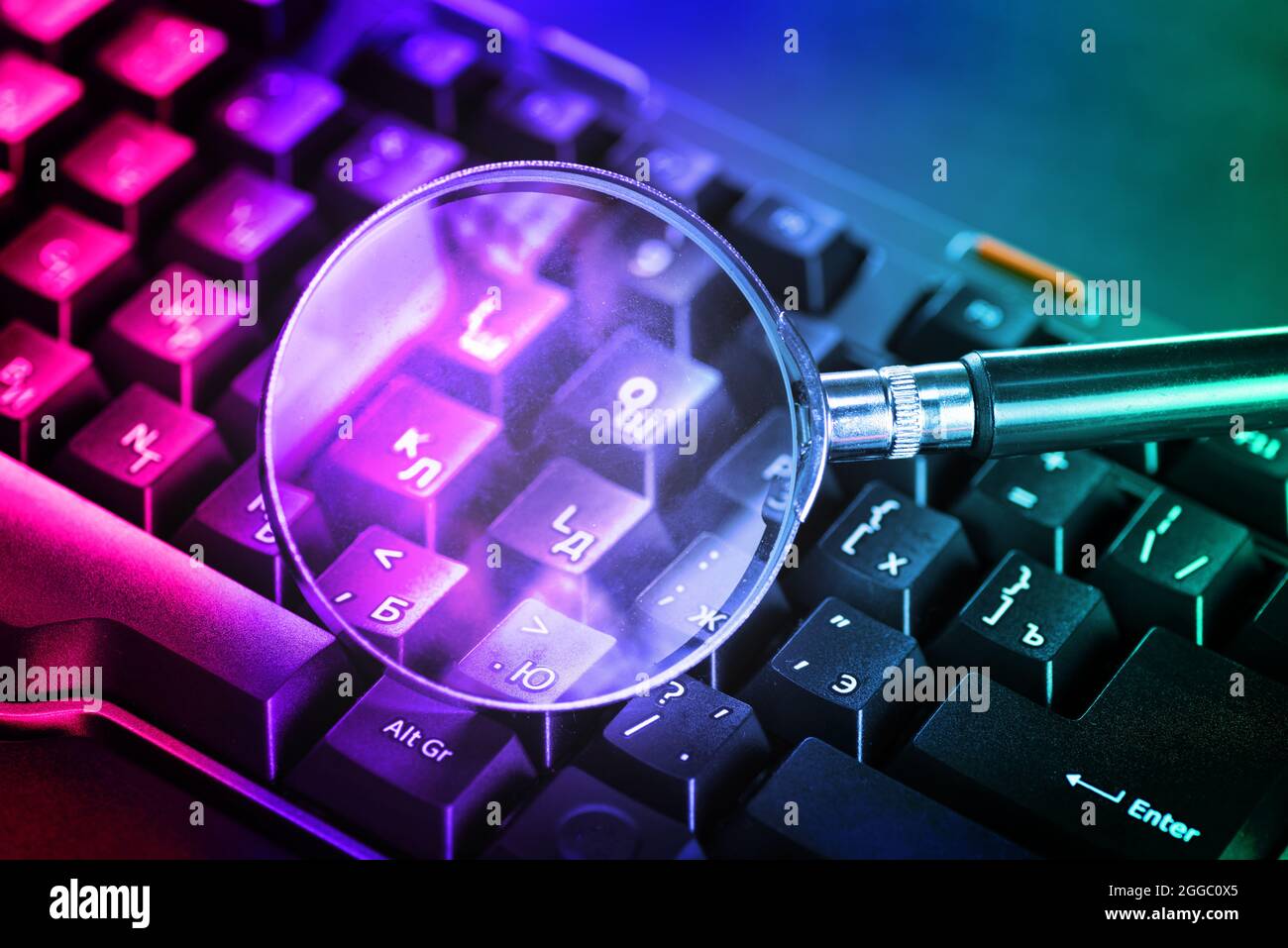 Magnifying glass on the keys of a black computer keyboard in neon light ...