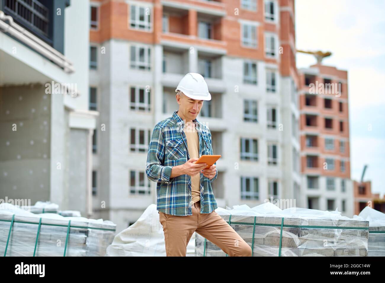 Focused construction engineer looking at the gadget in his hands Stock ...