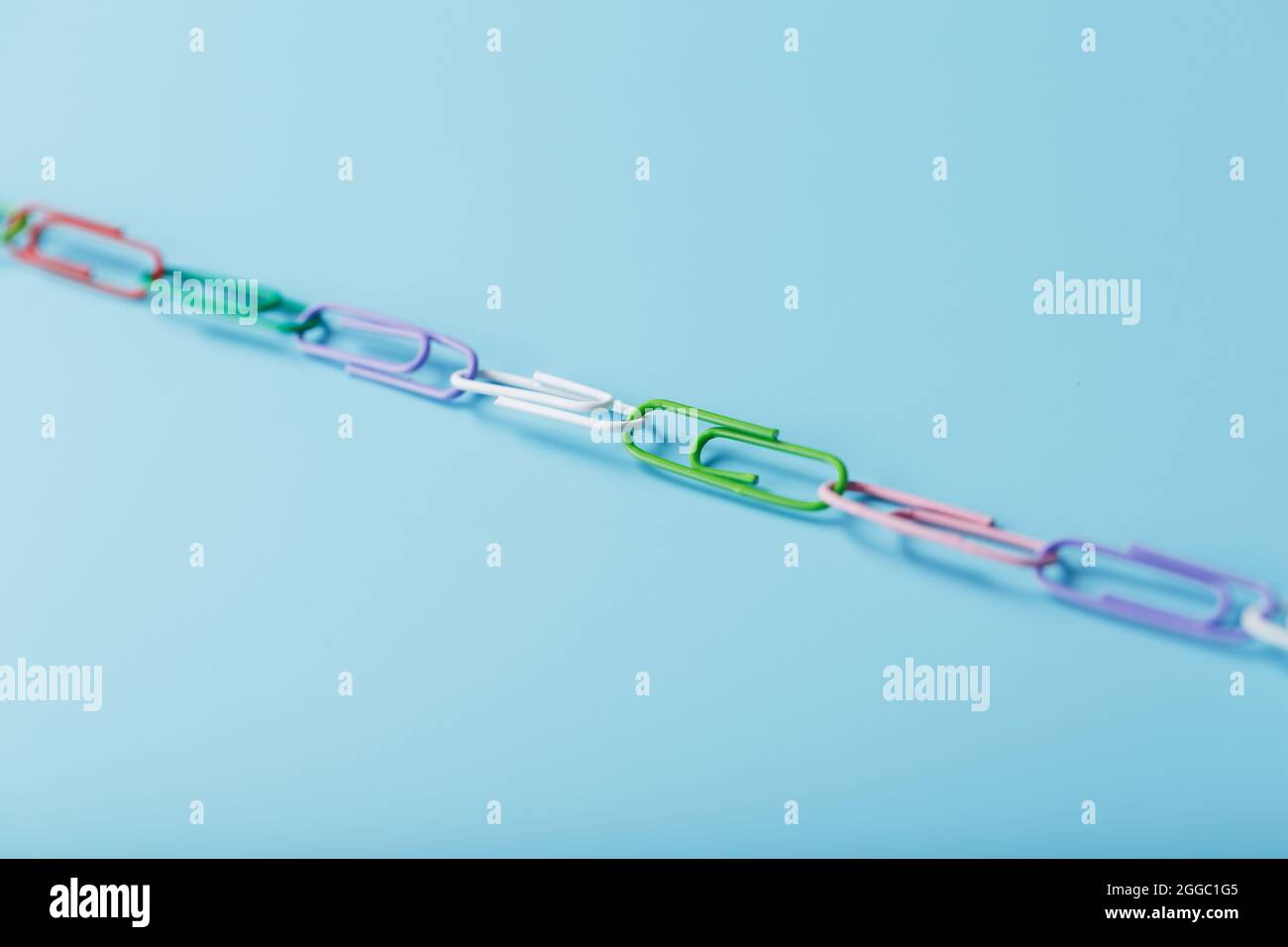 Interlocked colored paper clips in a line on a blue background with ...