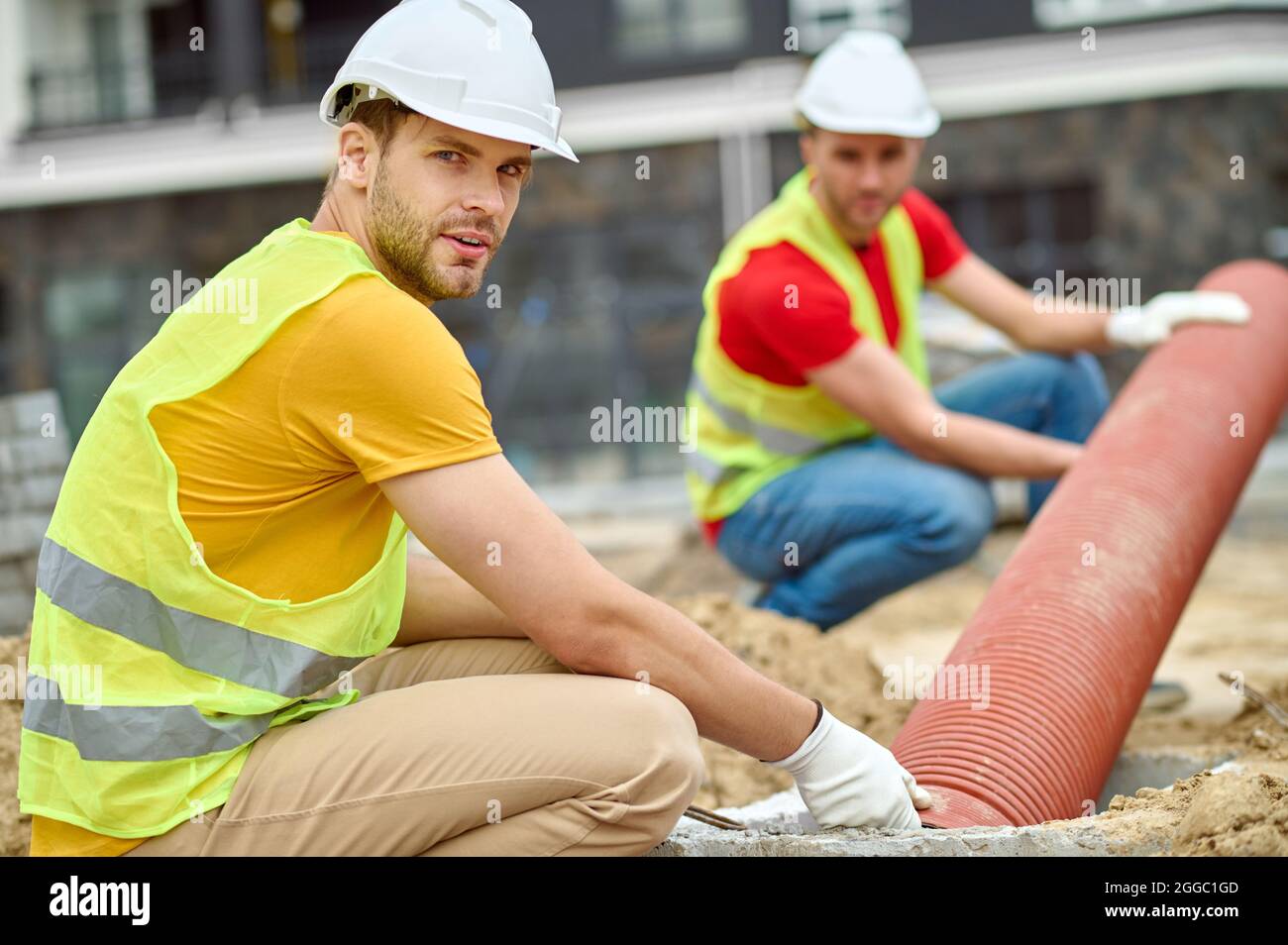 Skilled workers placing a corrugated drainage pipe into a concrete ...