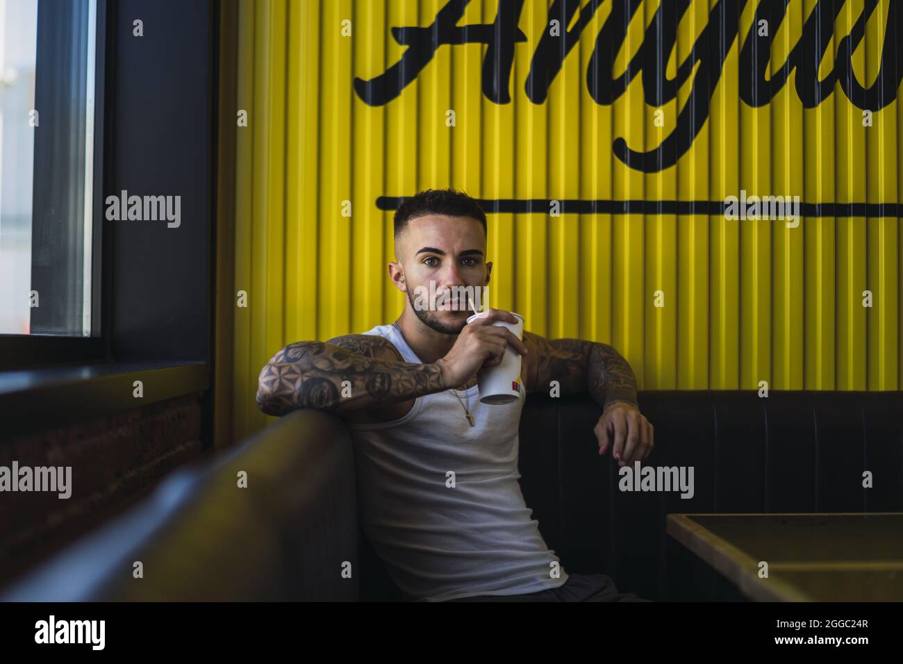 Young caucasian guy with cool tattoos sitting in the cafe and drinking ...