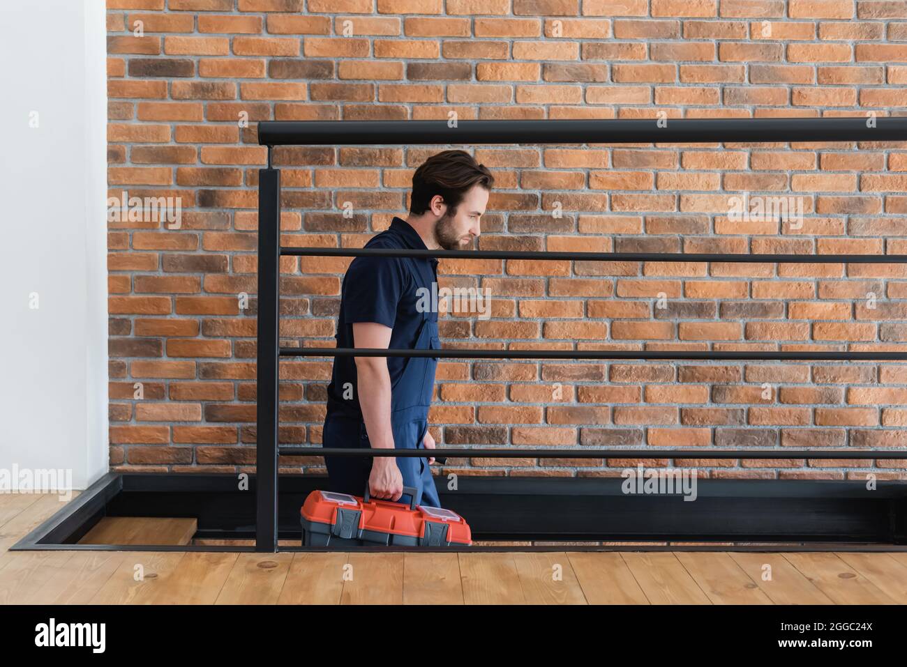 side view of foreman walking downstairs with toolbox Stock Photo - Alamy