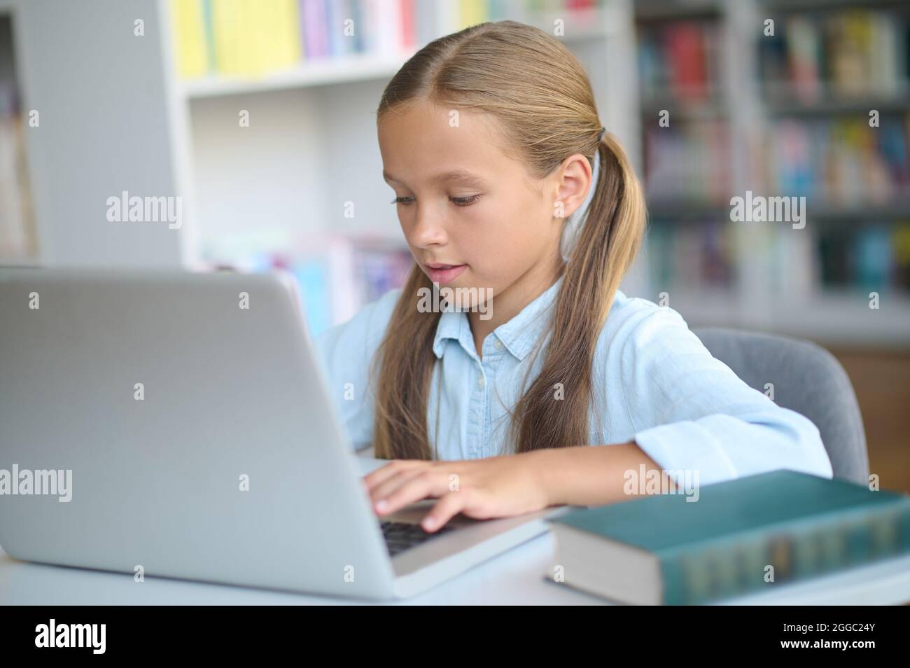 Focused young girl using a gadget in learning Stock Photo - Alamy