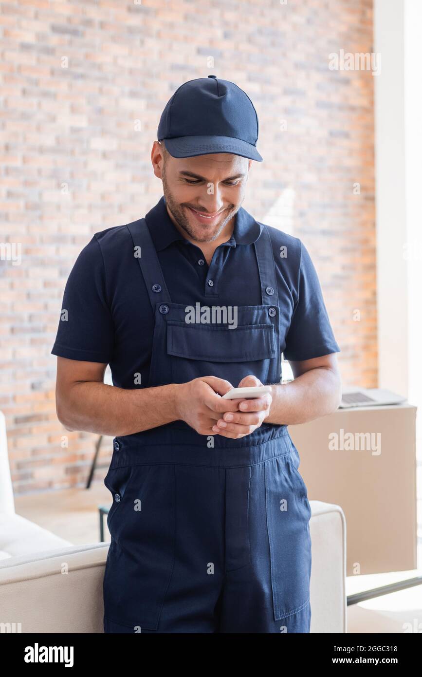 happy workman in overalls accepting order on mobile phone Stock Photo ...