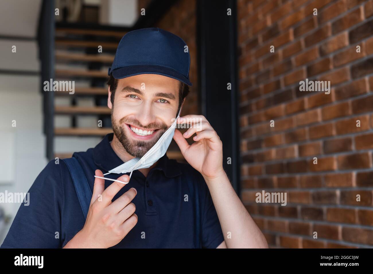 happy foreman smiling at camera and taking off medical mask Stock Photo ...