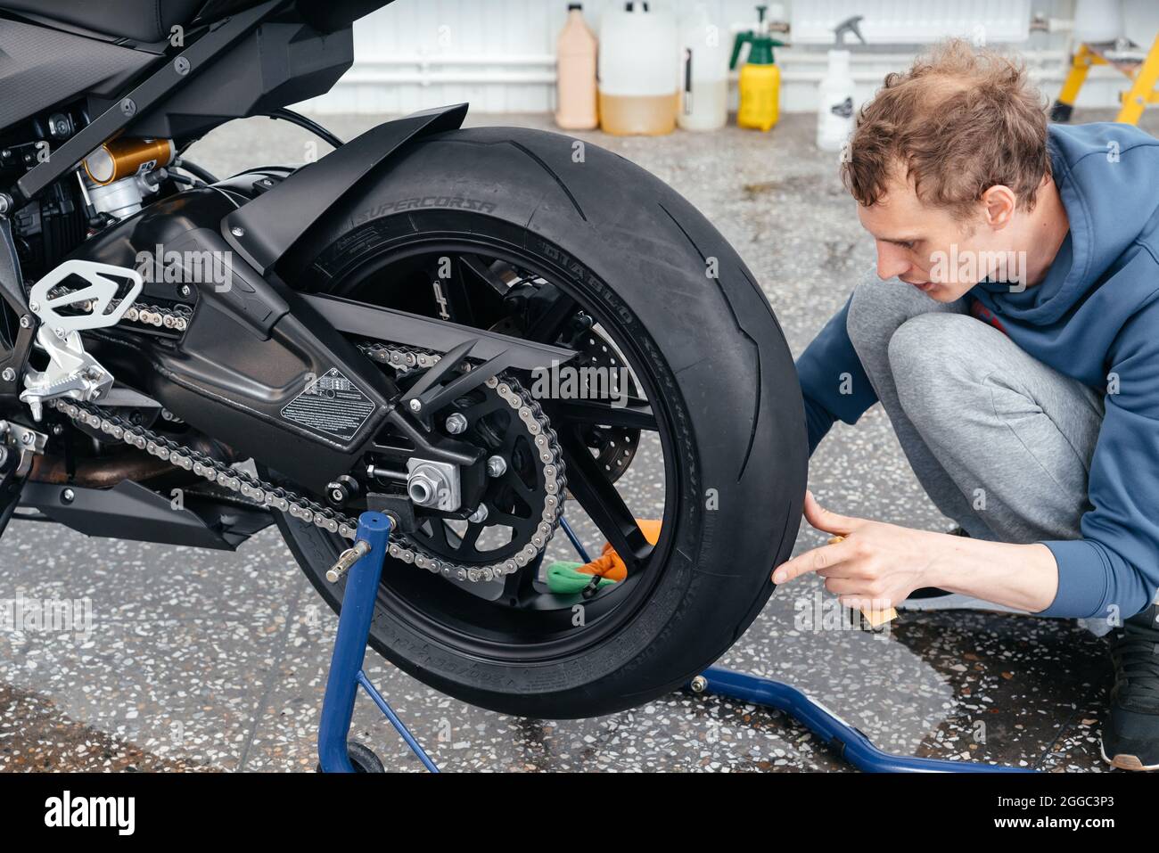 Young man cleaning or working with BMW black sportbike. Modern powerful ...
