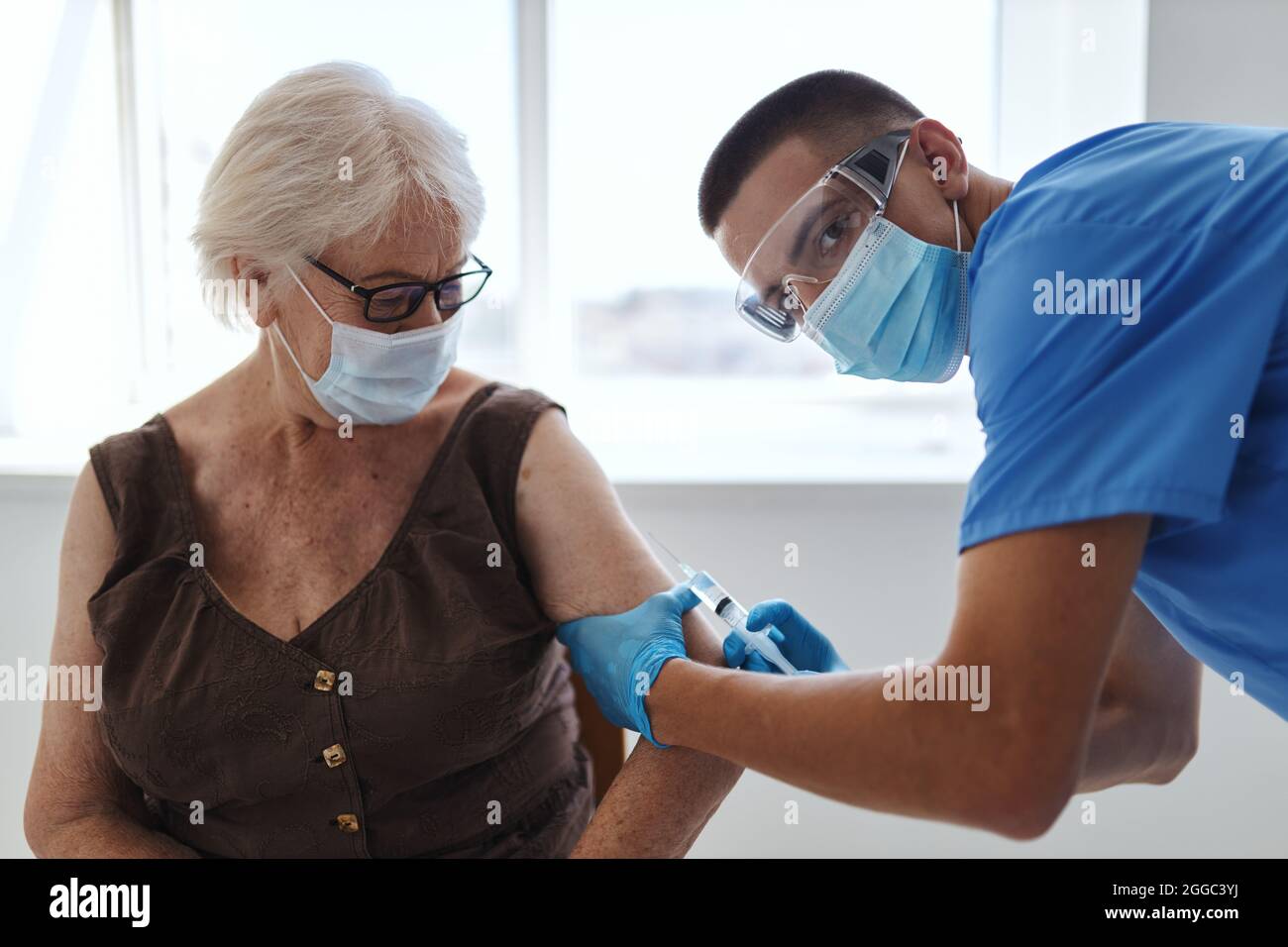 male doctor giving an injection to an elderly woman immunity protection ...
