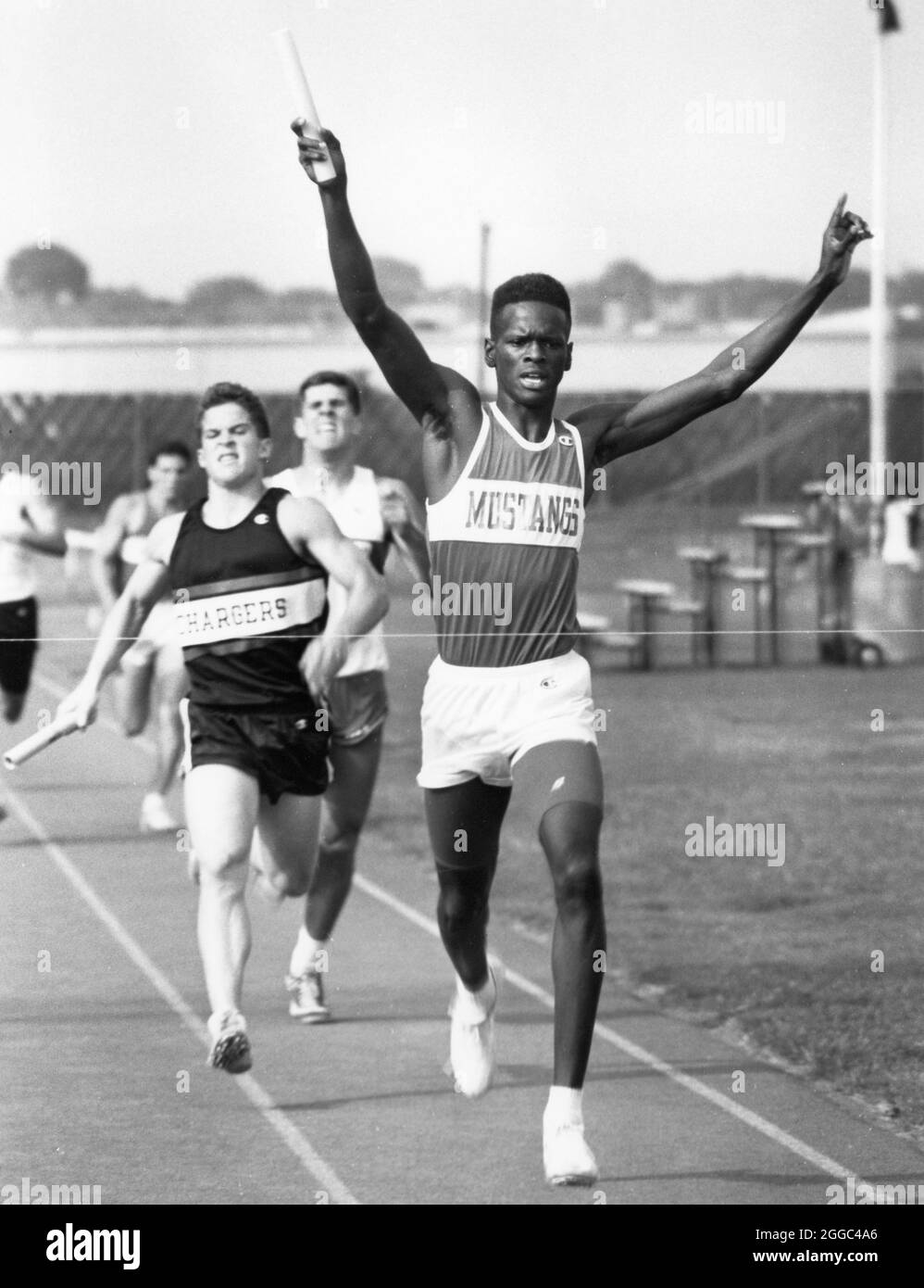 San Antonio Texas USA, circa 1993: Runner holding baton lifts arms in ...