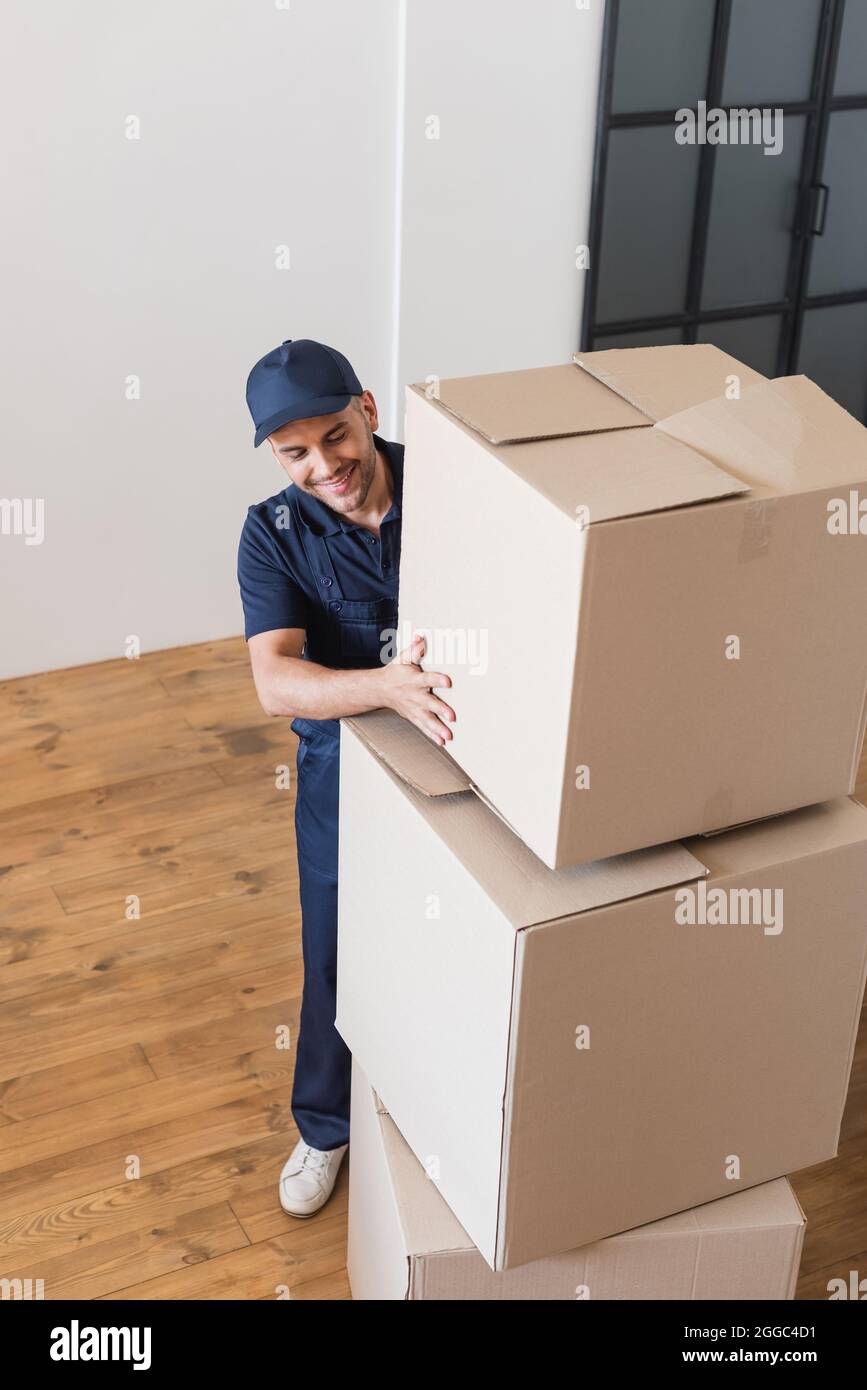 positive worker stacking large cardboard boxes in apartment Stock Photo ...