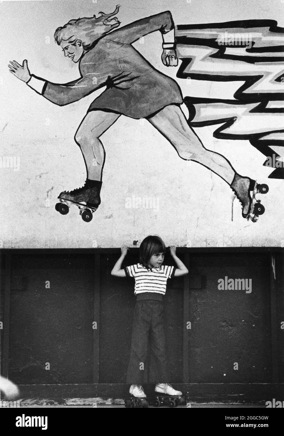 Luling Texas USA, circa 1982: Child stands underneath mural of roller ...