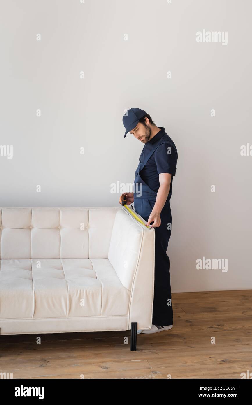 workman in uniform measuring white couch in living room Stock Photo - Alamy