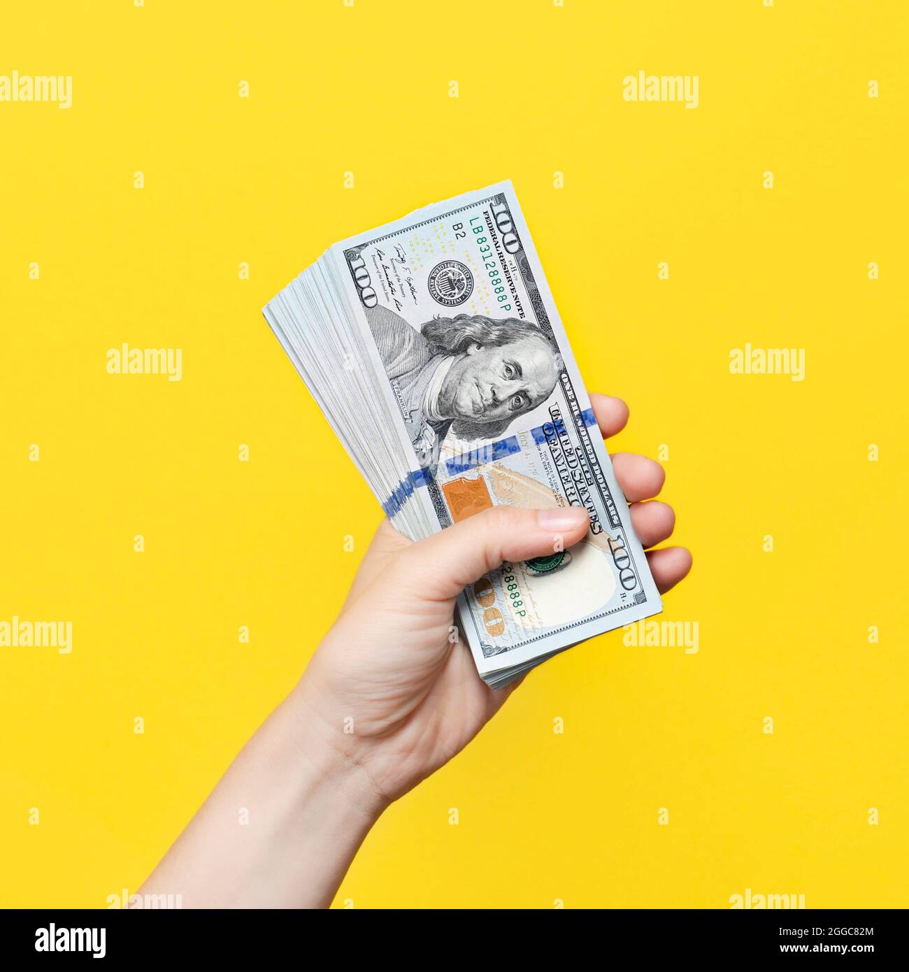 Hand holding a big stack of banknotes isolated on yellow background ...