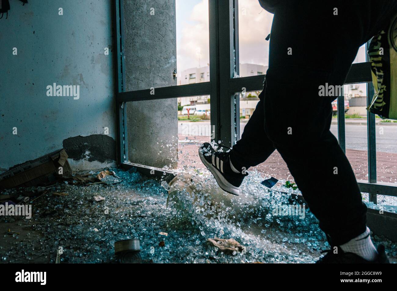 Closeup of a person's feet kicking glass pieces on the ground near a ...
