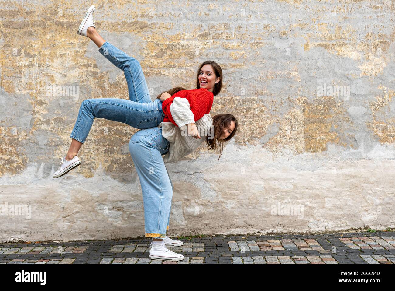 funny teenager carrying her best friend piggyback on the pavement at ...