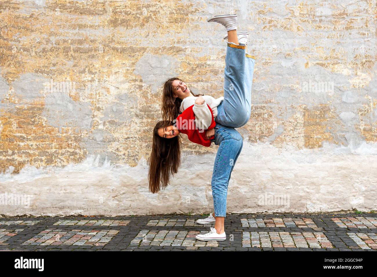 funny teenager carrying her best friend piggyback on the pavement at ...