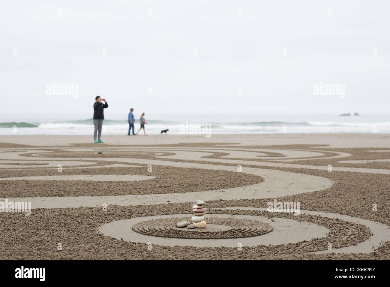 People walking in the distance next to a sand labyrinth in Bandon ...