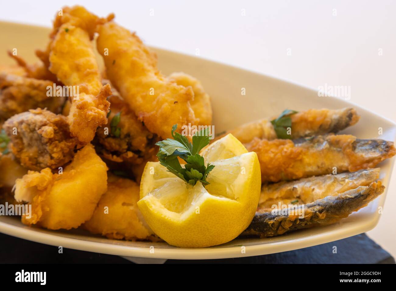 Closeup shot of fried shrimps and fish decorated with lemon and mint on ...
