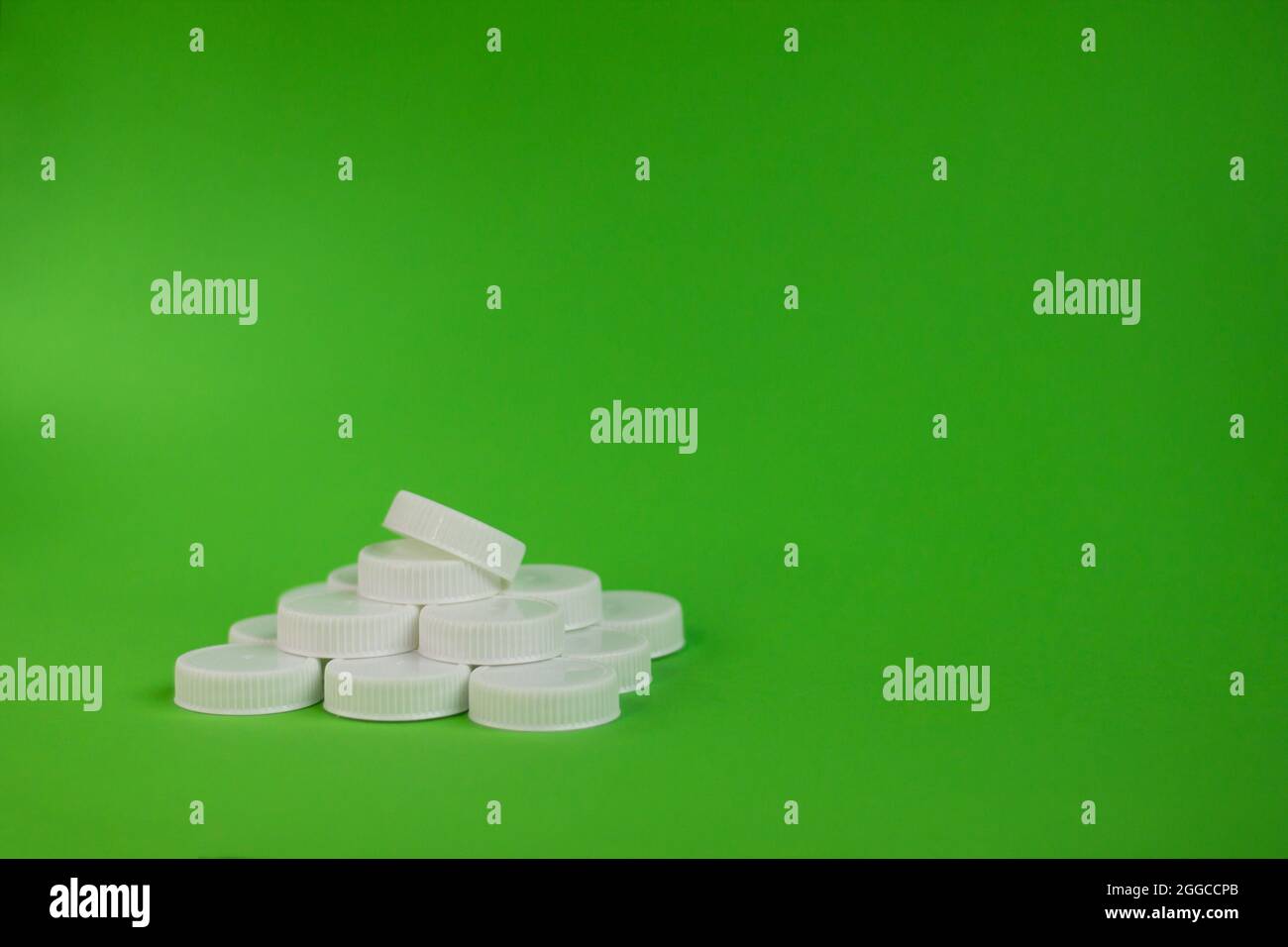 Pyramid of white plastic bottle caps for recycling on a green ...