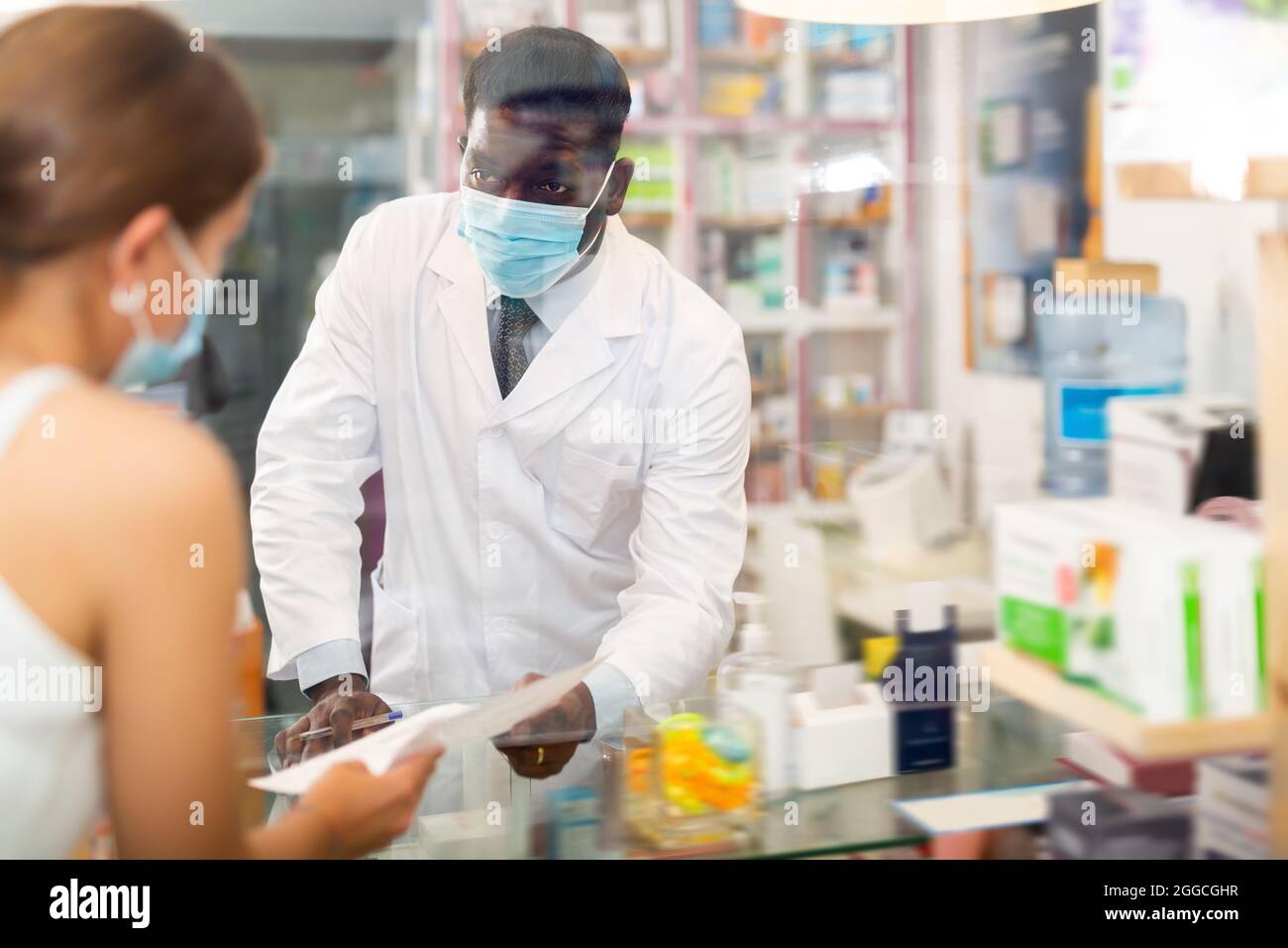 Pharmacist standing behind counter and talking with client Stock Photo ...