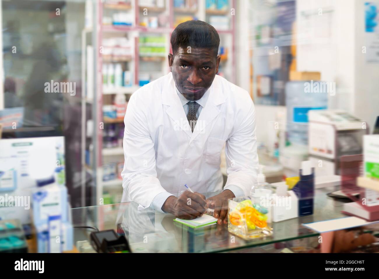 Pharmacist standing behind counter Stock Photo - Alamy