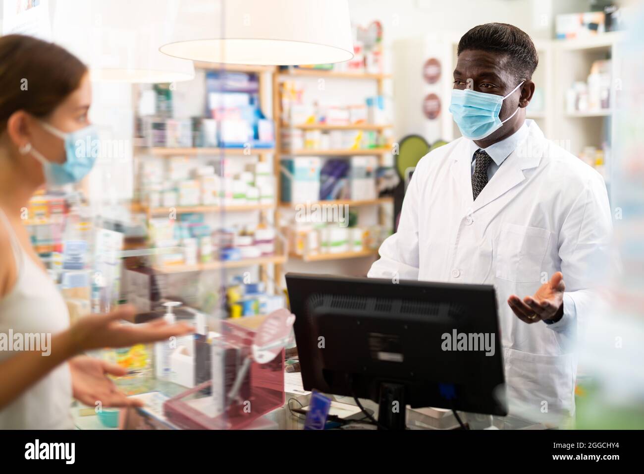 Pharmacist standing behind counter and talking with client Stock Photo ...