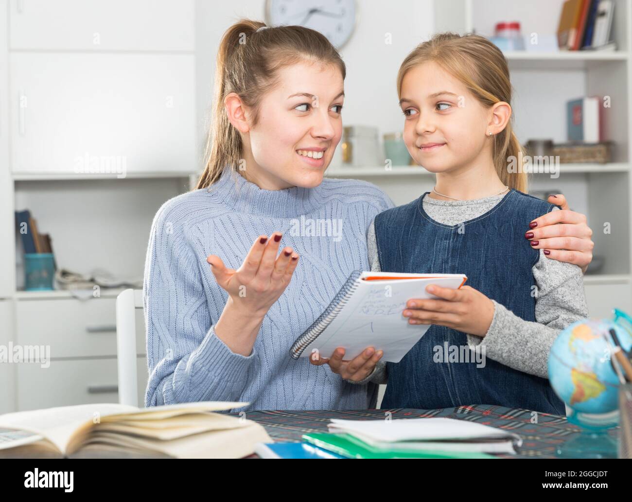 Girl and mother doing home task Stock Photo - Alamy