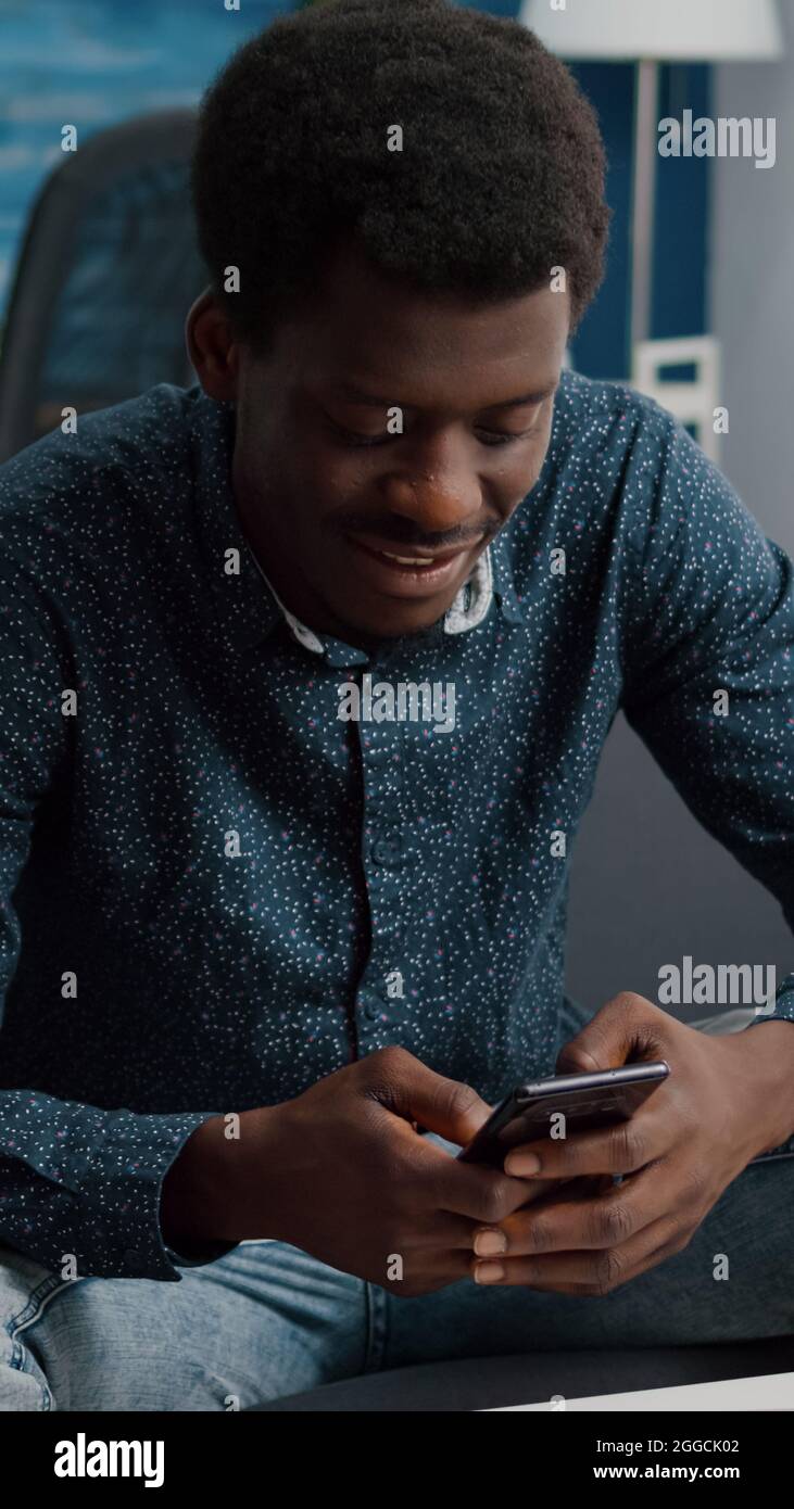 Black guy in his living room using phone to browse social media ...
