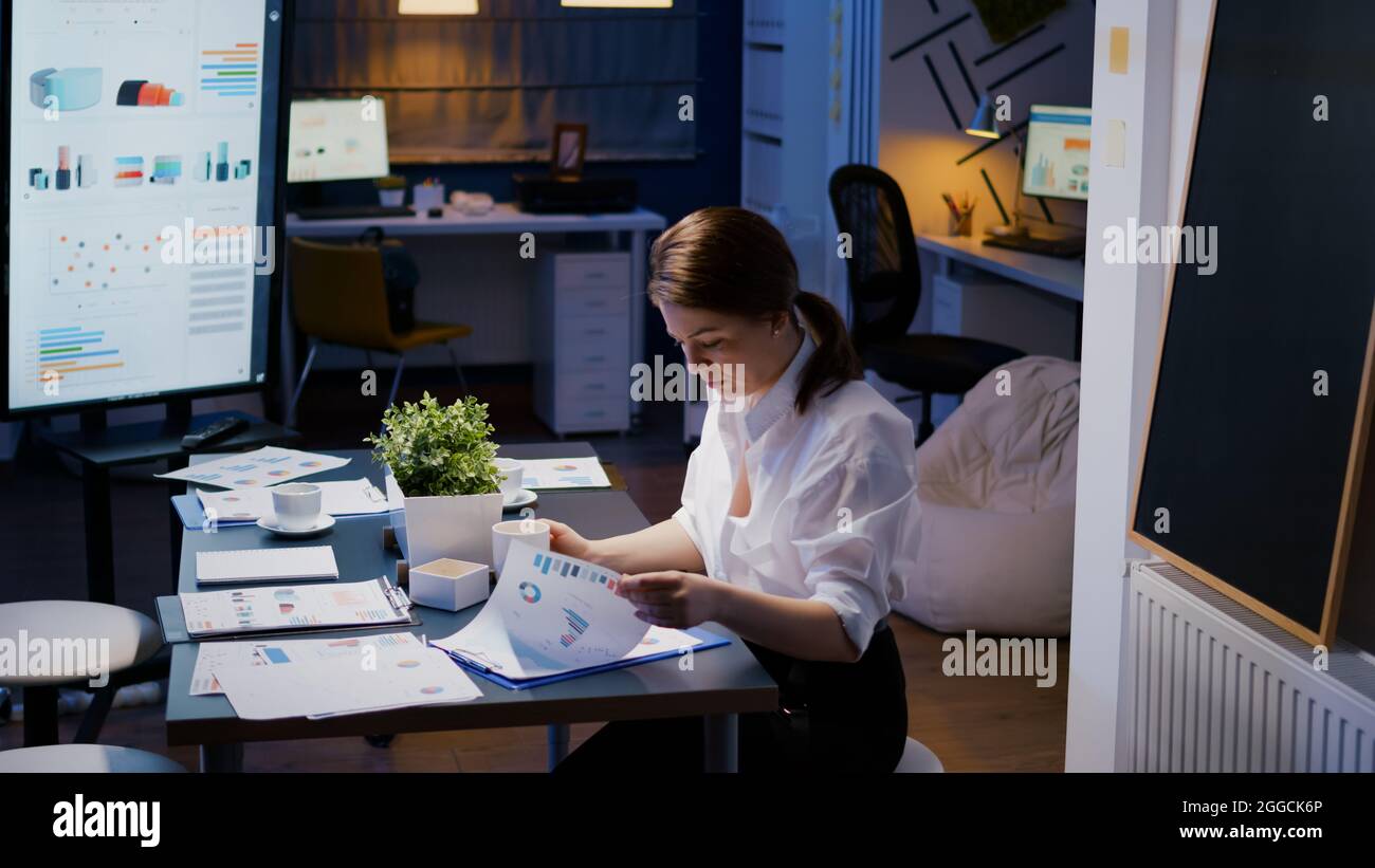 Workaholic businesswoman looking at reports presentation on monitor ...