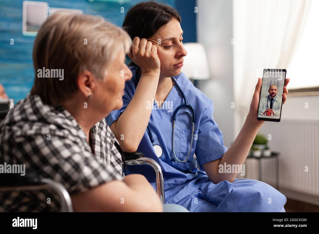 Social worker holding smartphone for disabled senior retired woman in ...