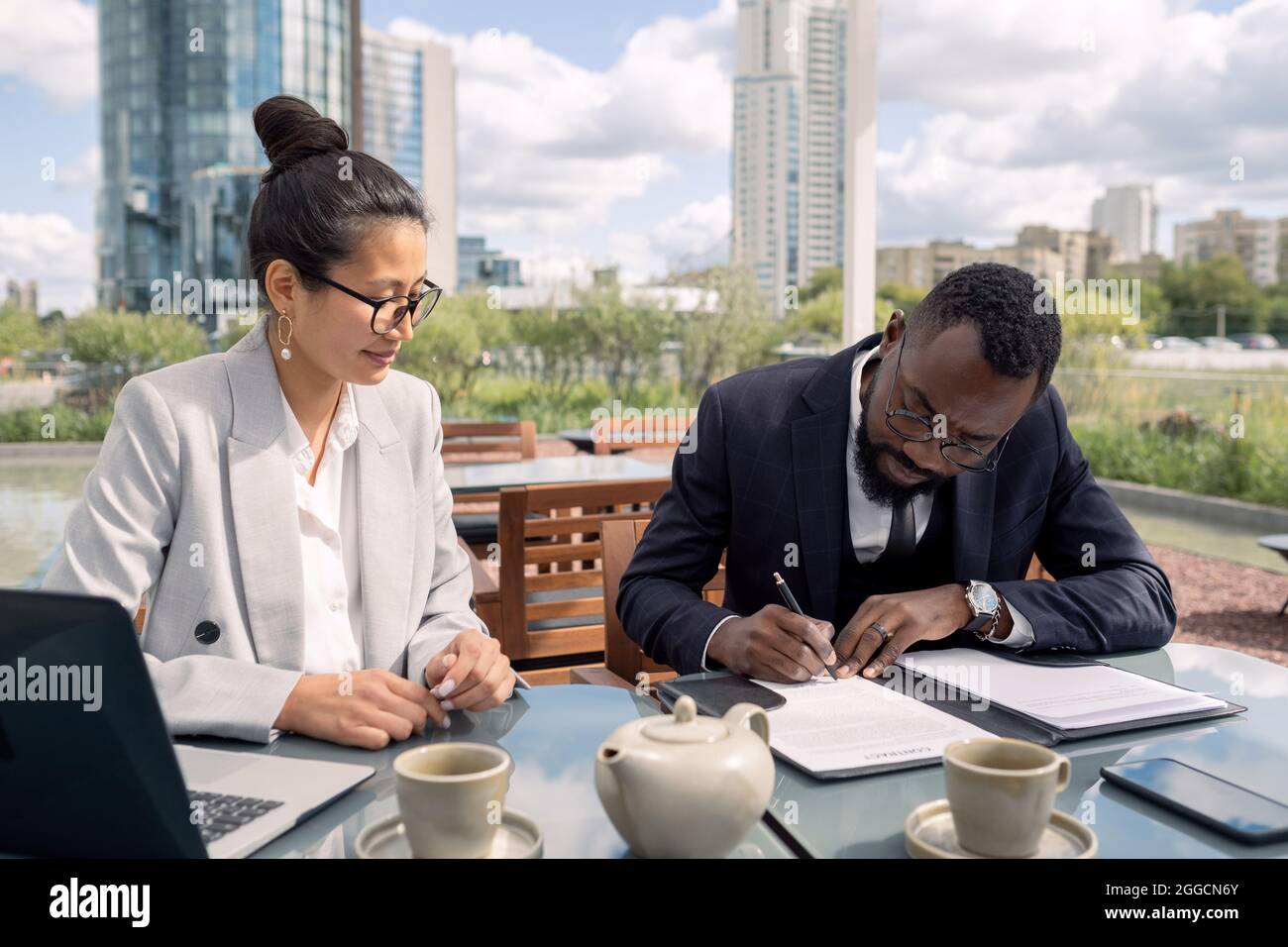 African businessman in elegant suit signing contract after negotiation ...