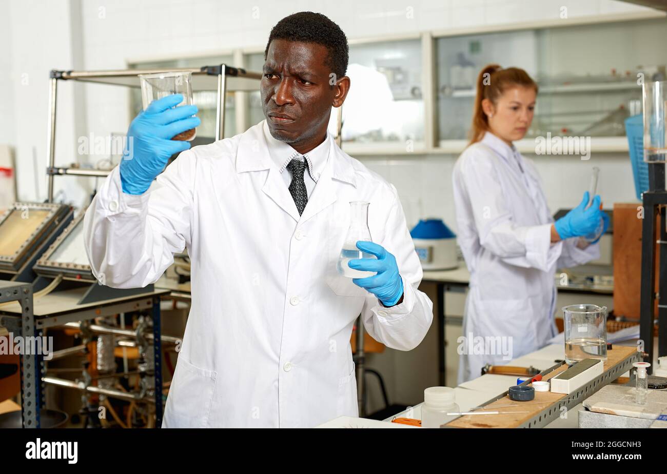 Serious male scientists with glass test tubes during chemical ...