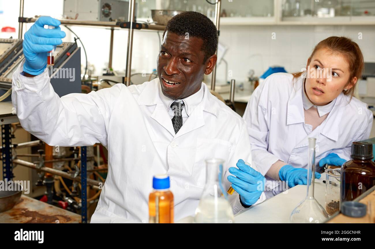 Male scientist with test tubes checking for result of chemical ...